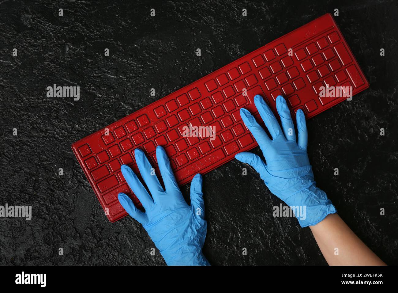 Woman in rubber gloves with computer keyboard on dark background Stock ...