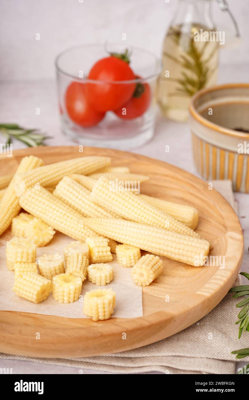 Plate with cut and whole canned baby corn cobs on light background ...