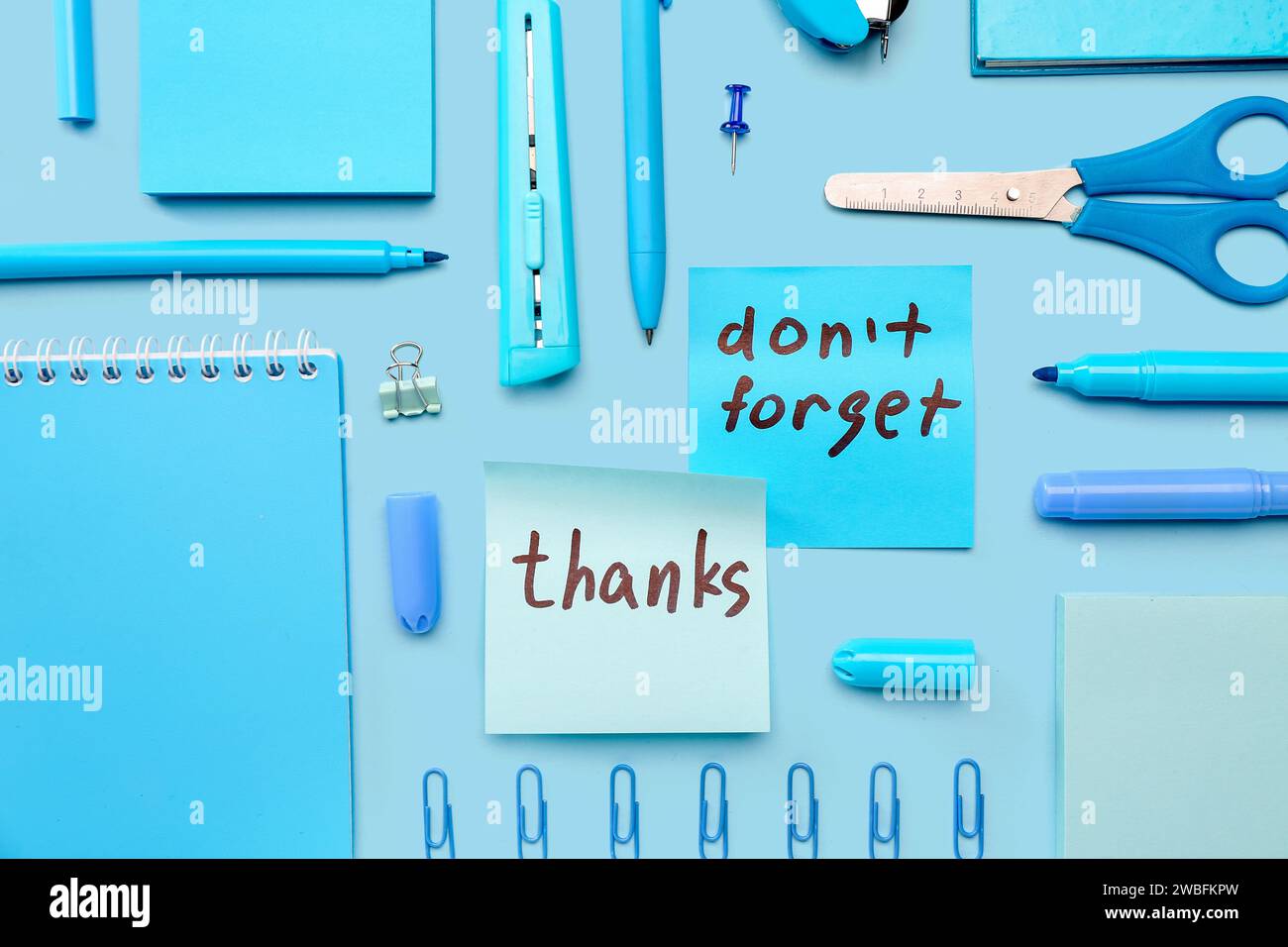 Sticky notes with word THANKS, text DON'T FORGET and stationery on blue ...