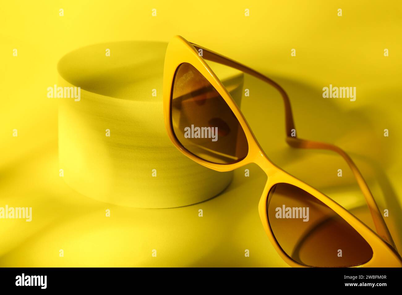 Podium with stylish sunglasses on yellow background Stock Photo - Alamy