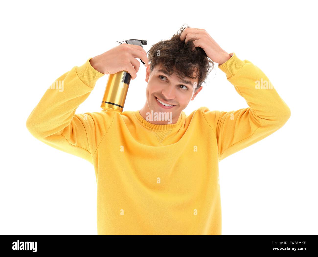 Handsome young man applying hair spray on his curly hair against white ...