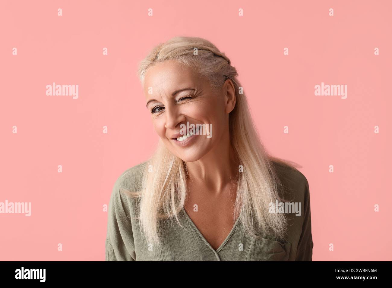 Mature woman winking on pink background, closeup Stock Photo - Alamy