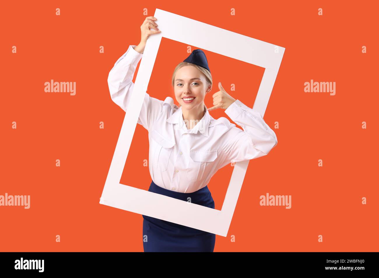 Young stewardess with frame showing "call me" gesture on orange ...