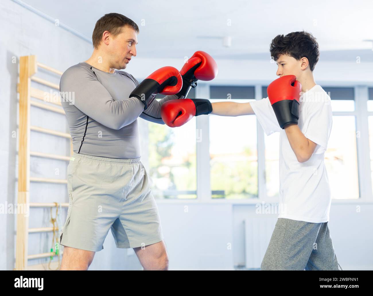 Middle-aged man and teenage boy training boxing during sports classes ...