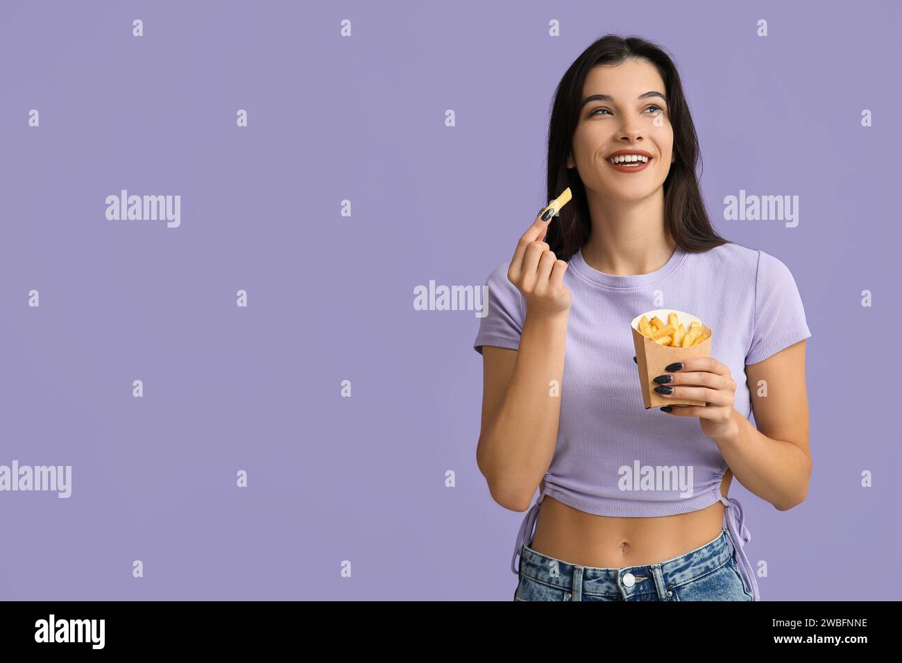 Beautiful young woman with french fries on purple background Stock ...