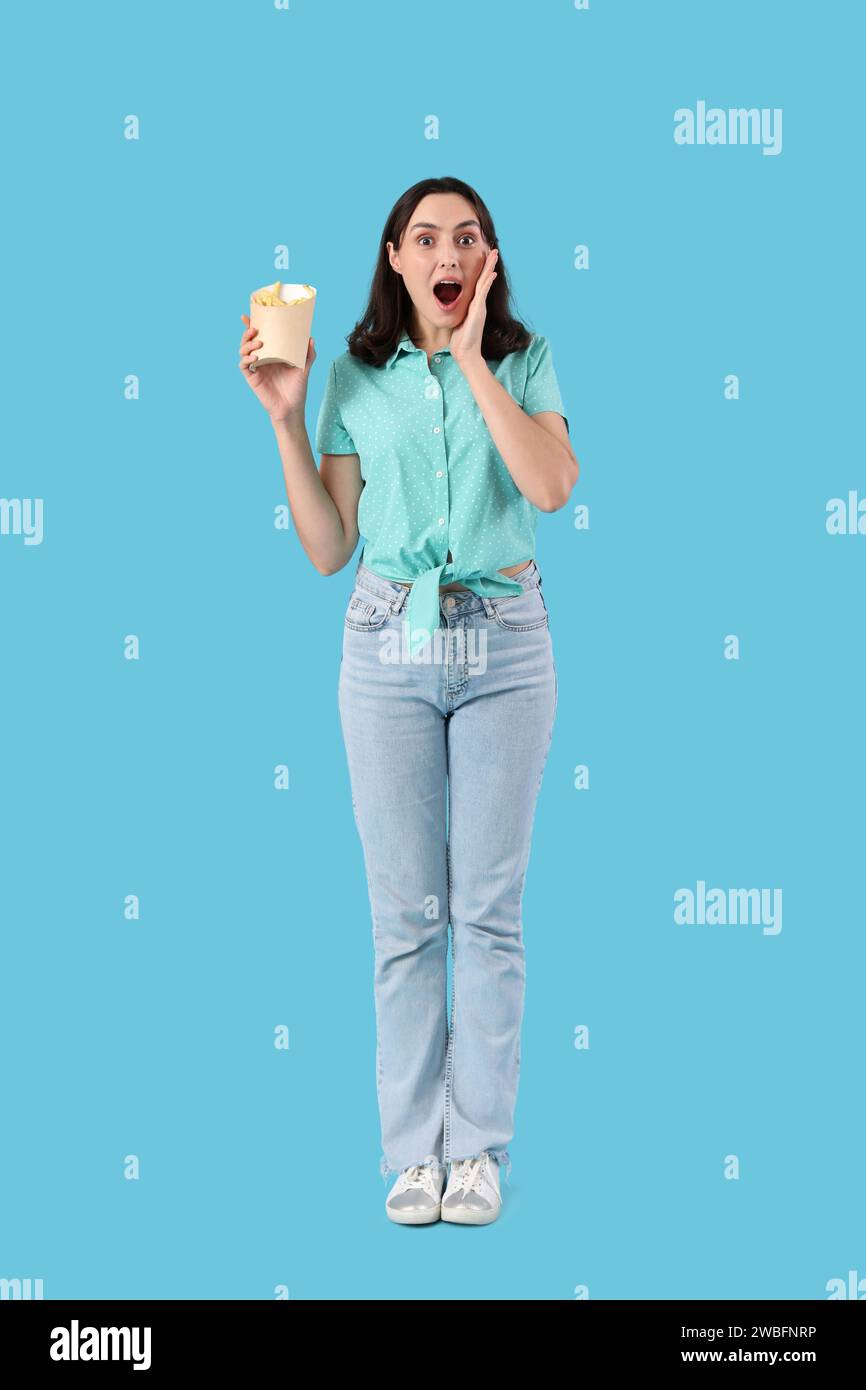 Shocked young woman with french fries on blue background Stock Photo ...
