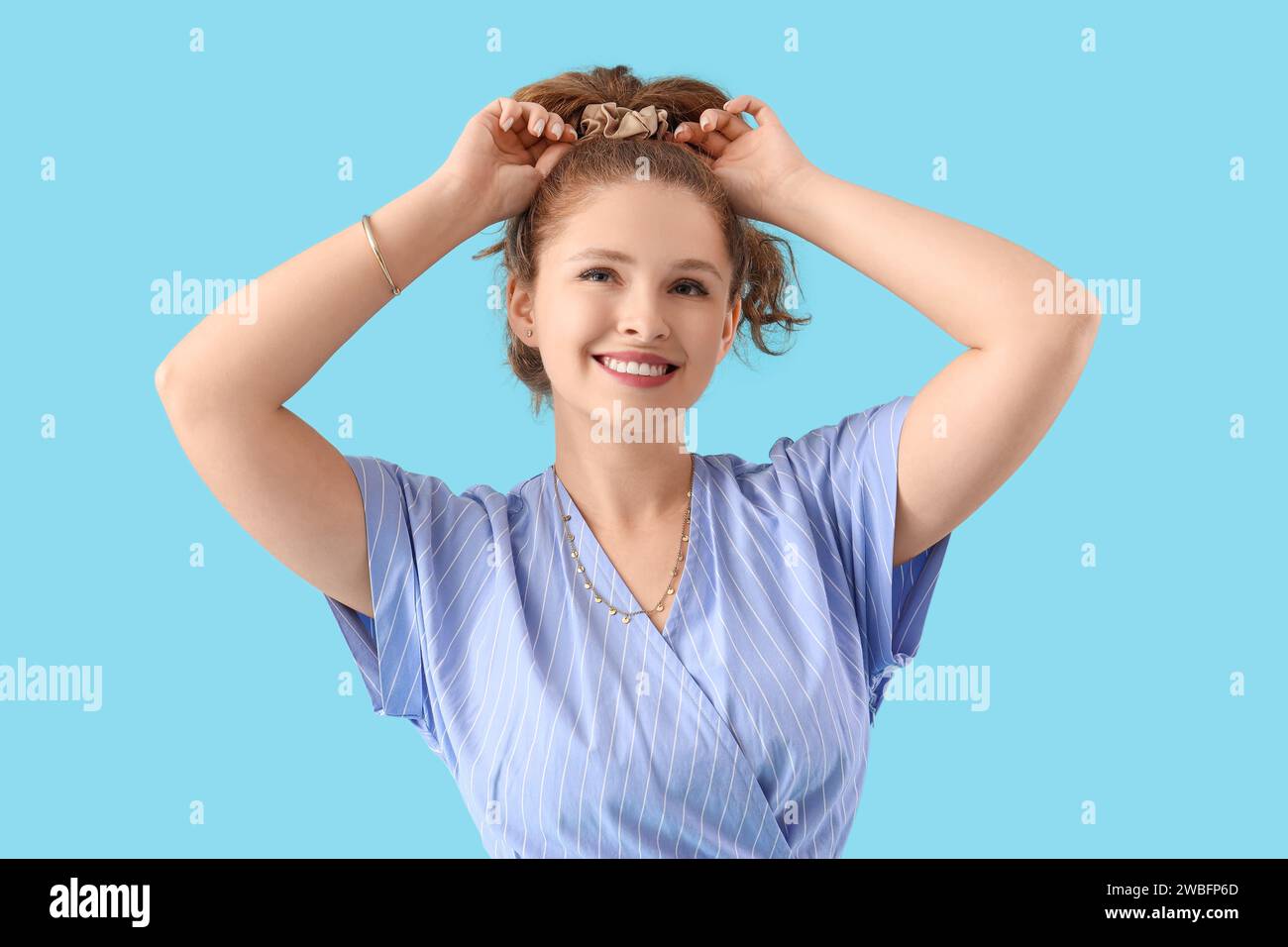 Young redhead woman with ponytail and scrunchy on blue background Stock ...