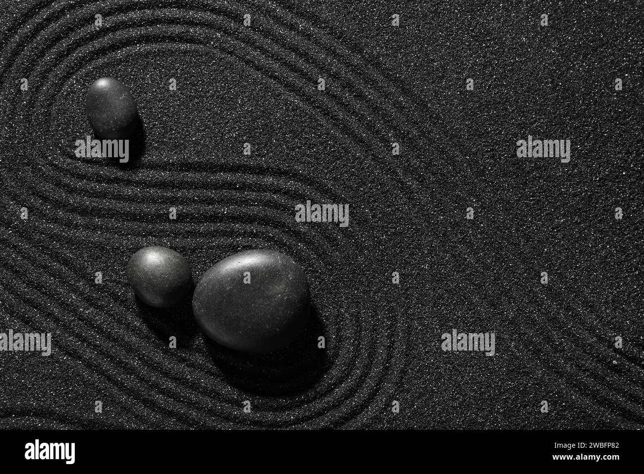 Stones on dark sand with lines in Japanese rock garden, top view. Zen ...