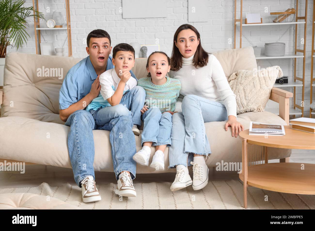 Shocked family watching TV on sofa at home Stock Photo - Alamy