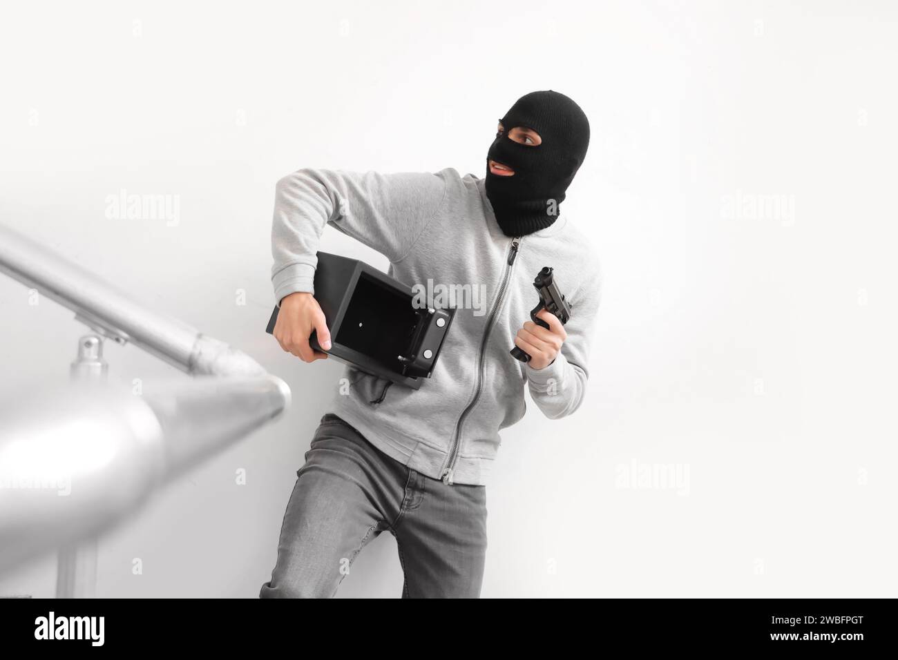 Male thief with safe and gun escaping in stairway Stock Photo - Alamy