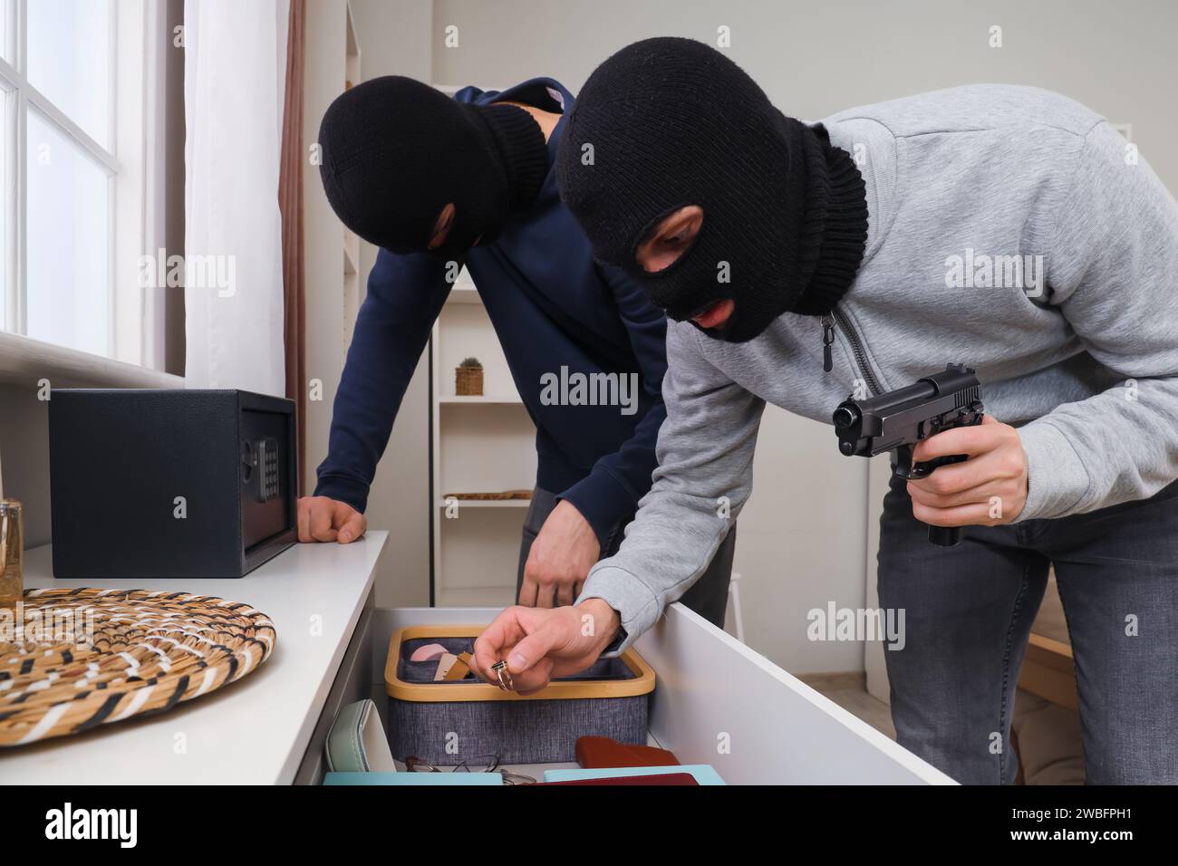 Male thieves stealing valuables from open drawer in room Stock Photo ...