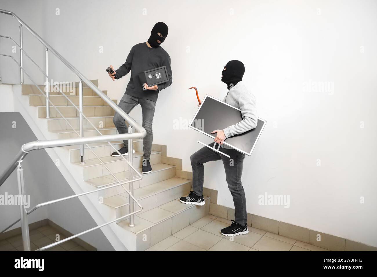 Male thieves with stolen valuables escaping in stairway Stock Photo - Alamy