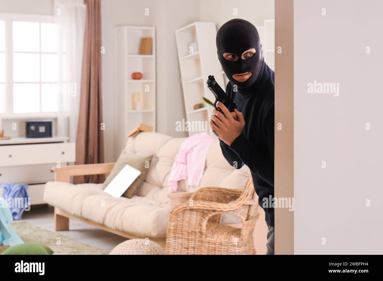 Male thief with gun behind wall in room Stock Photo - Alamy