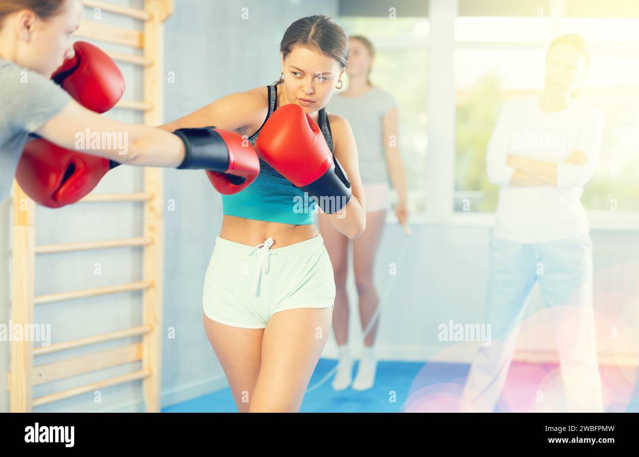 Adolescent girl in boxing gloves practicing punches in sparring during self defence course Stock ...