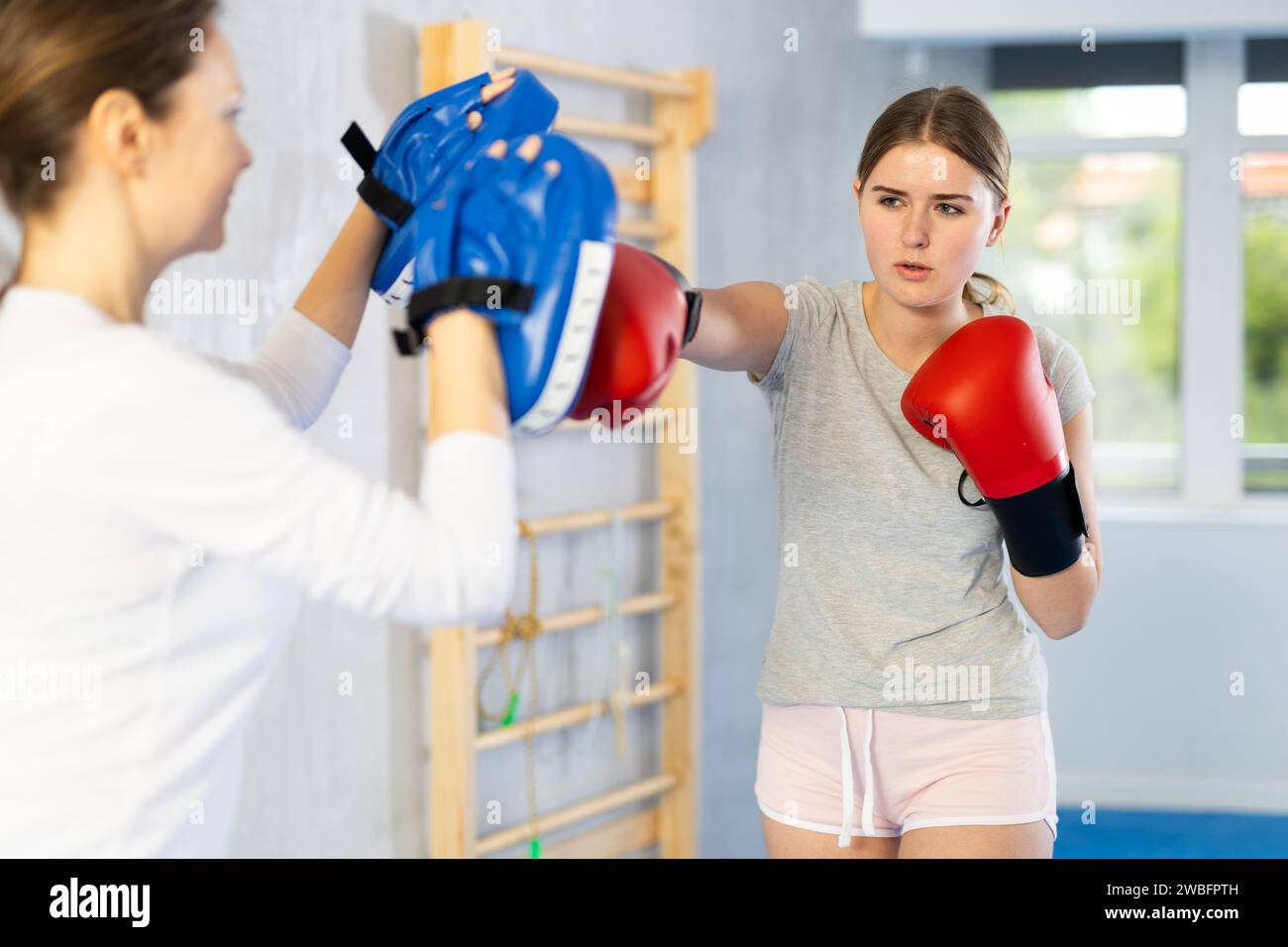 Girls works out strength and speed of boxing punch mitts with help of ...