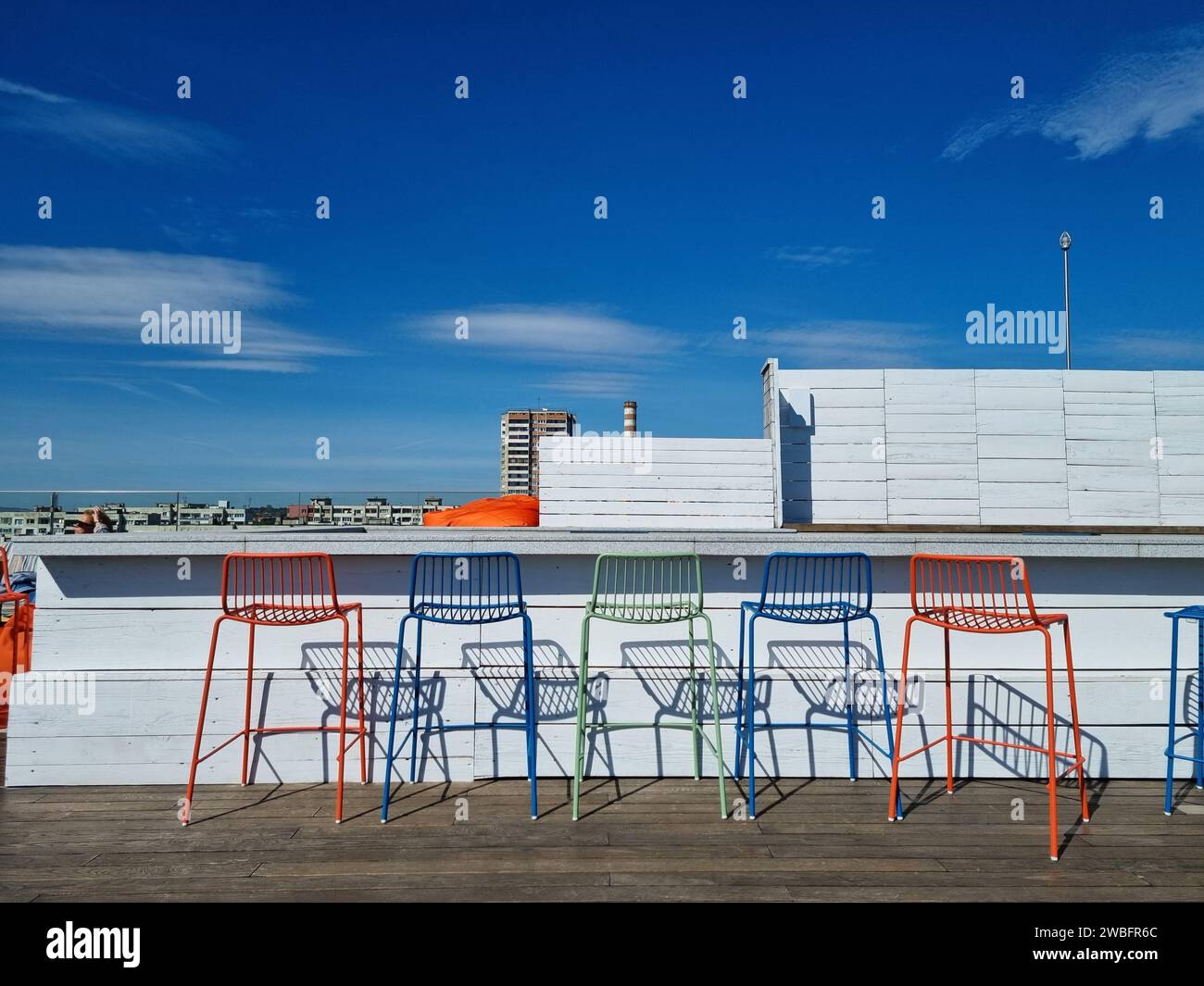 Four vibrant metal stools are arranged around a wooden deck, with a ...