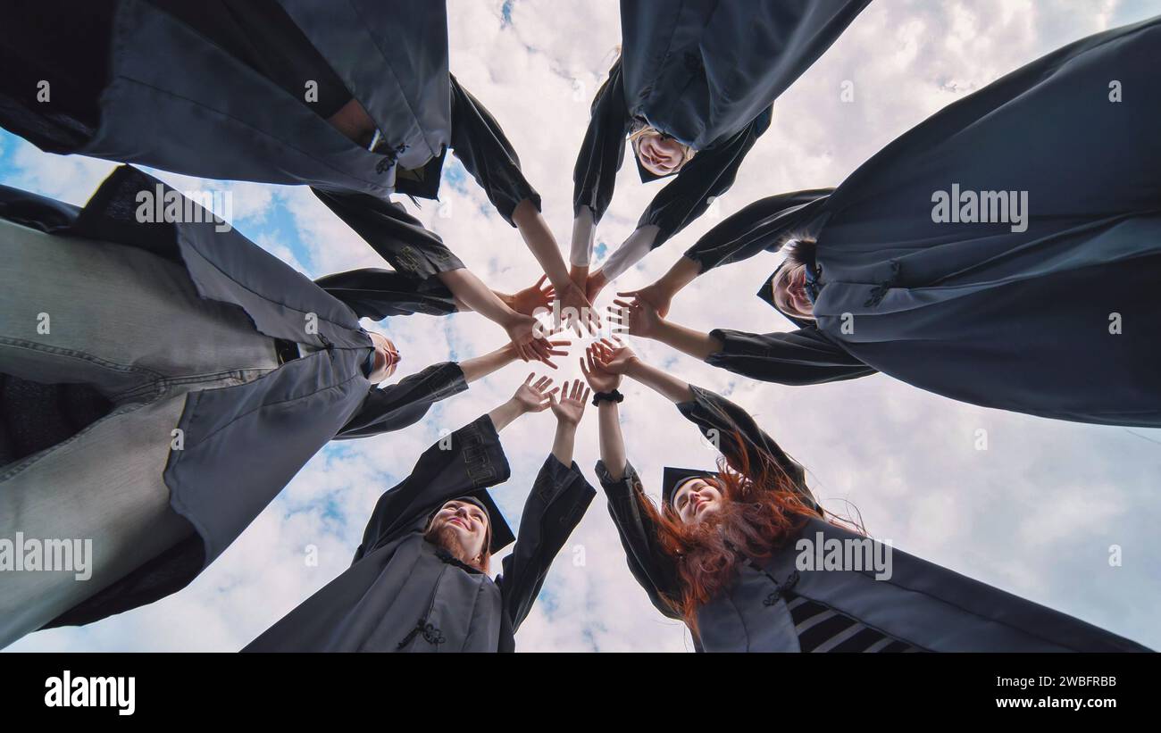 Group of happy successful graduates in academic hats and robes standing ...