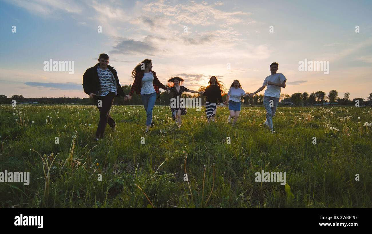 Merry friends run off into the sunset holding hands Stock Photo - Alamy