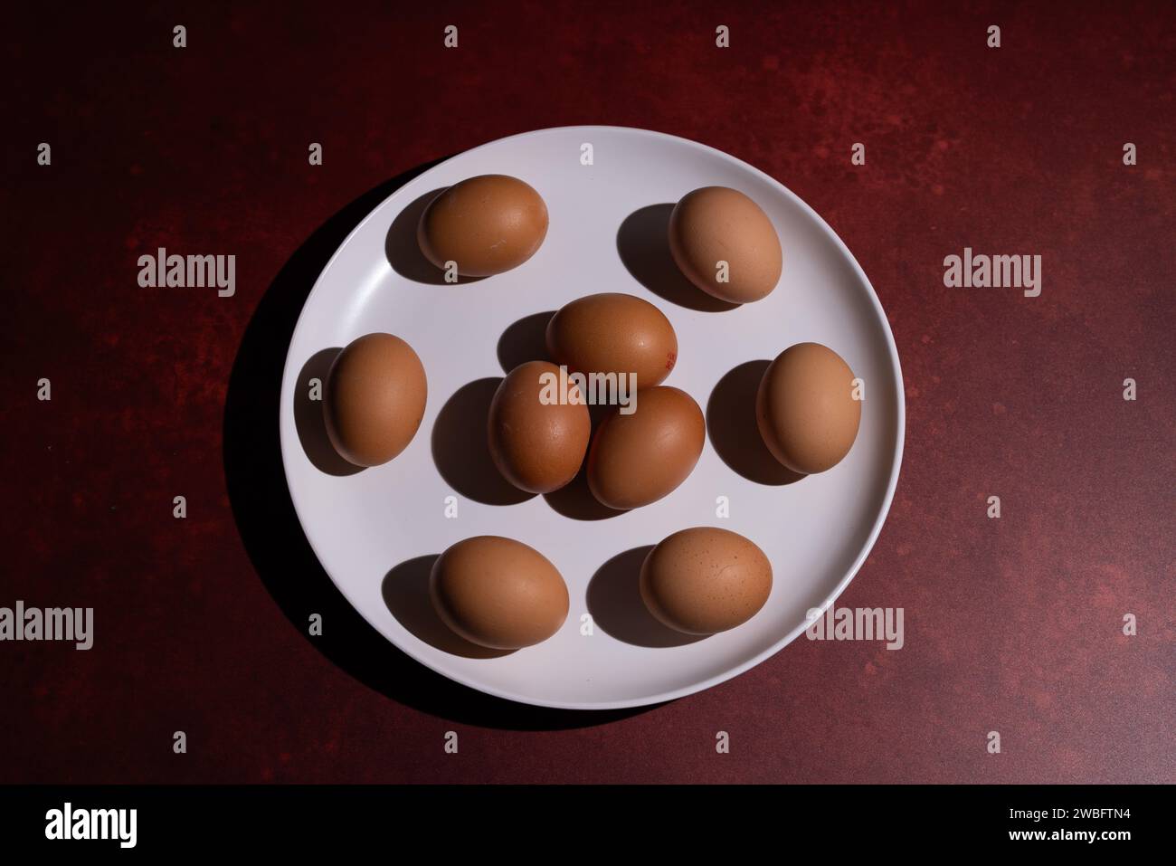 9 eggs in a elegant plain white dish against a red rich background with ...
