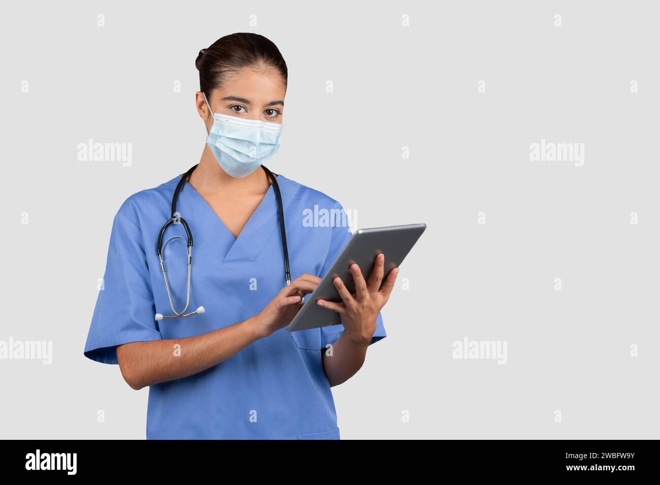 Focused european nurse in blue uniform with a surgical mask using a ...