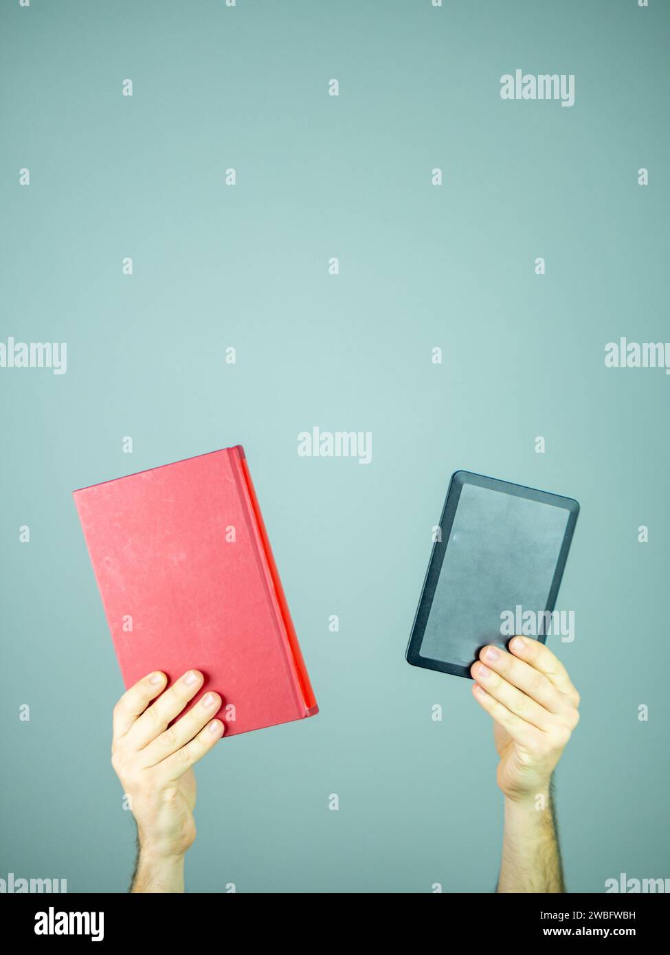Two hands holding a red cover paper book and an electronic book Stock ...
