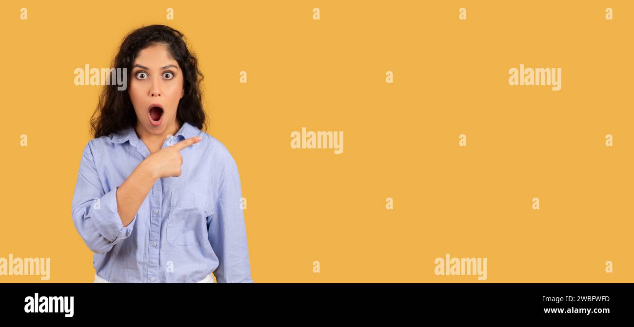 Wide-eyed woman in a light blue shirt expresses shock and surprise ...