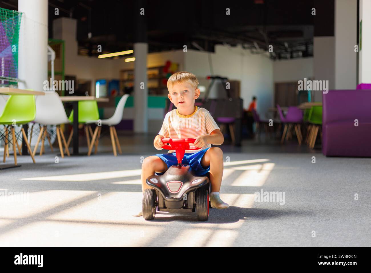 Young Child Riding Toy Car in Play Area Stock Photo - Alamy