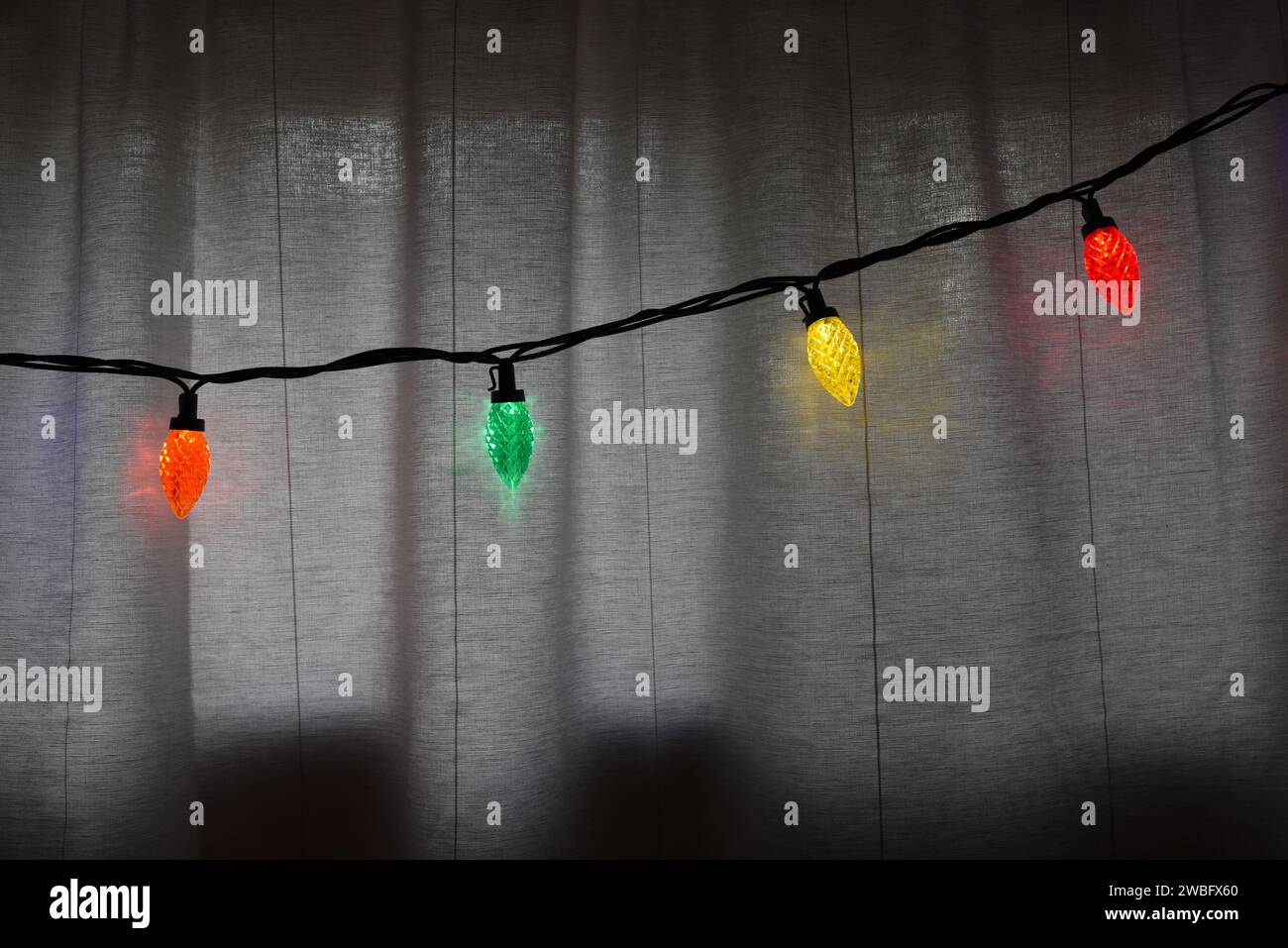 Christmas lights hang in front of a curtained window Stock Photo - Alamy