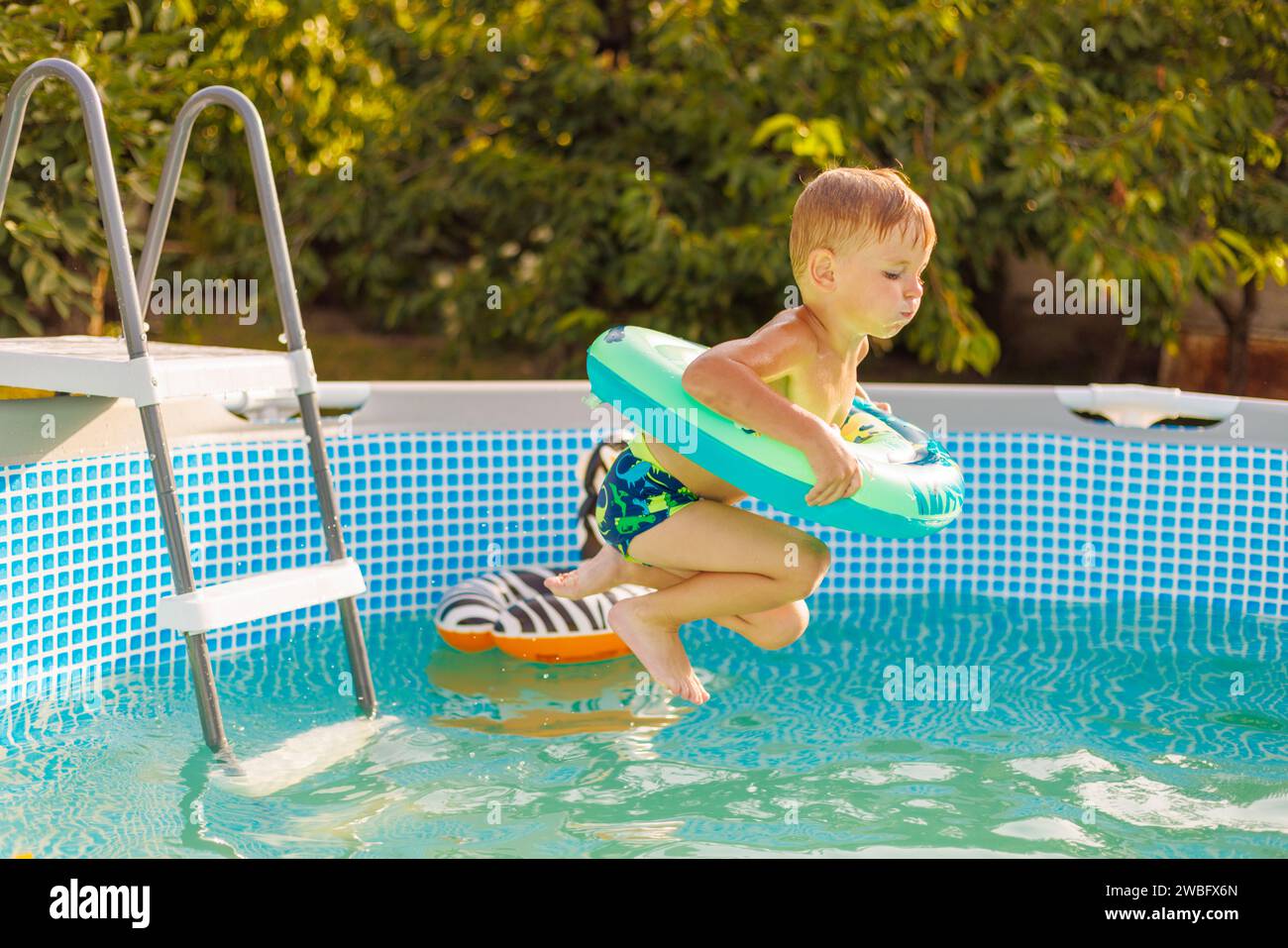 Young Boy Jumping into Pool with Float Ring Stock Photo - Alamy