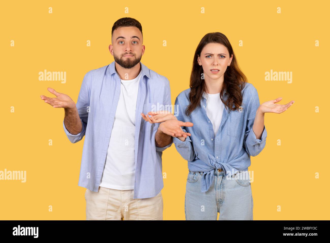 Confused couple shrugging, uncertain expressions, yellow backdrop Stock ...
