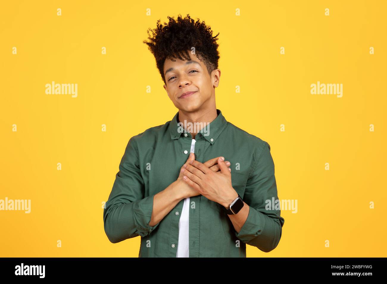 Smiling young black man holding hands over chest Stock Photo - Alamy