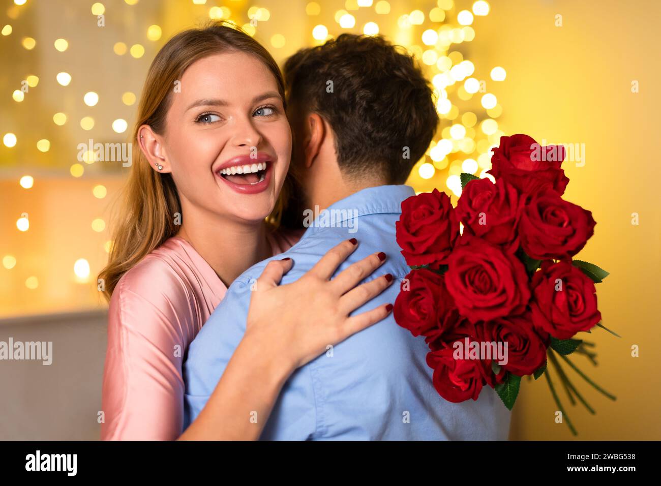 Radiant woman hugging man with bouquet of roses, gleeful surprise Stock ...