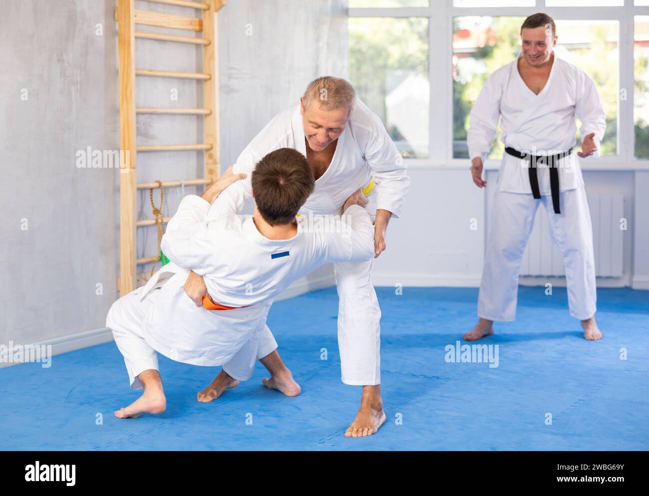 Senior man, karate sensei, engaging kumite with young guy in training ...