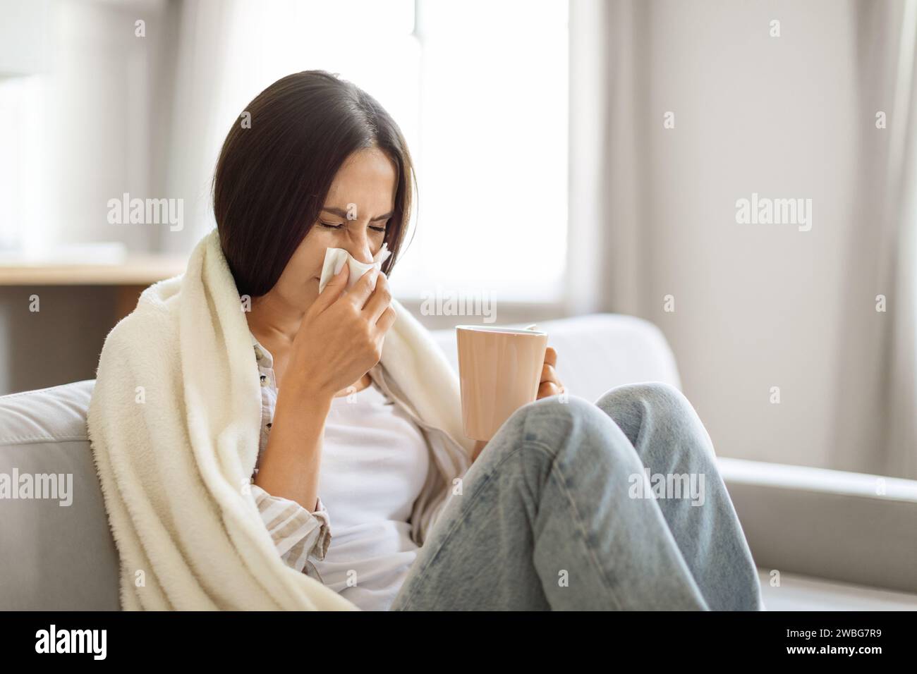 Young woman feeling sick at home, blowing her nose with tissue Stock ...