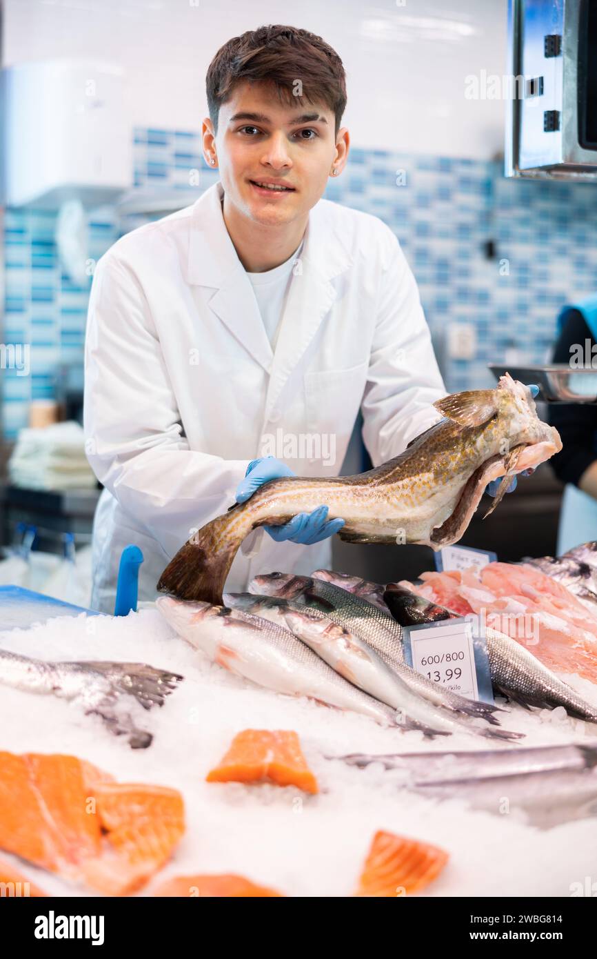 Seller of fish department of a supermarket demonstrates fresh atlantic ...