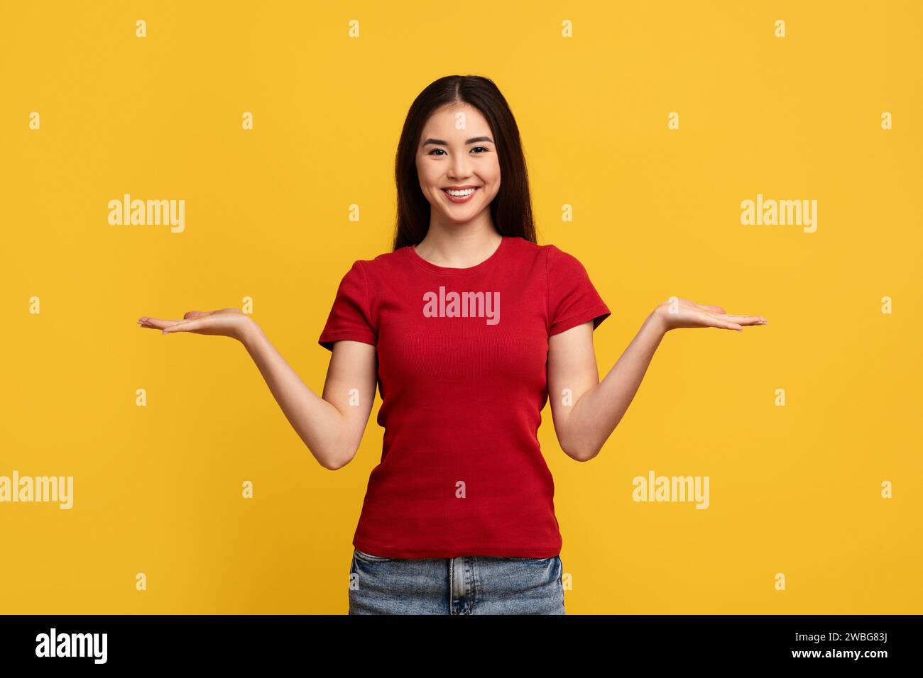 Cheerful young korean woman holding something invisible on both hands ...