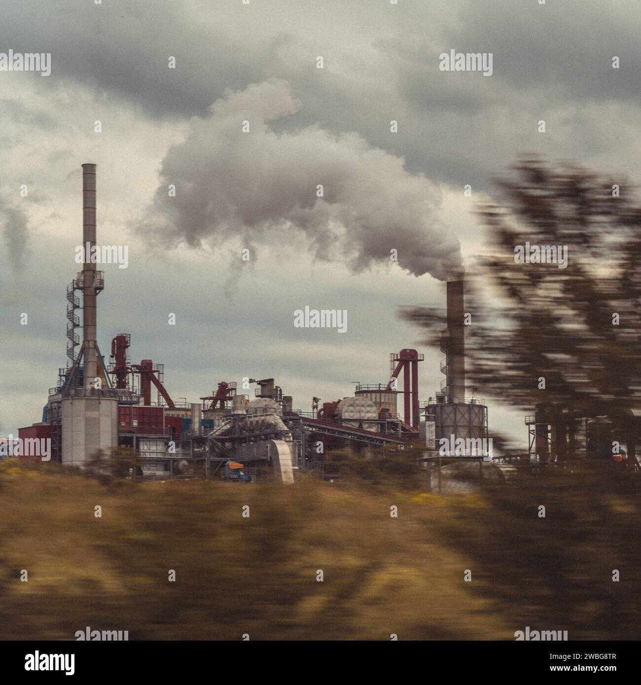 An industrial factory with smokestacks releasing smoke into the ...