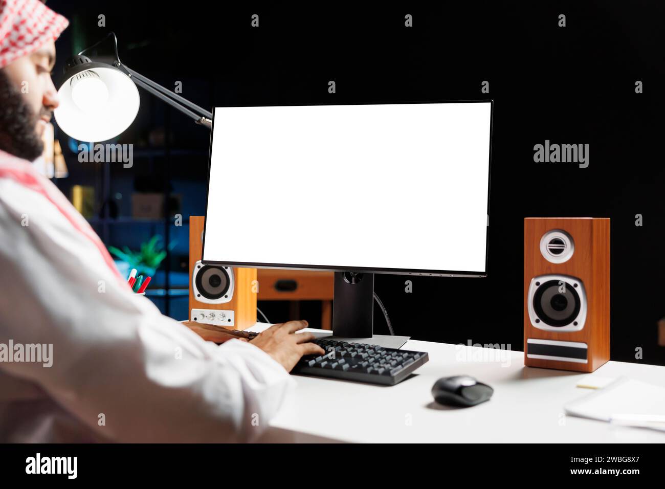 Image portrays Muslim guy seated at his workstation at home, his ...