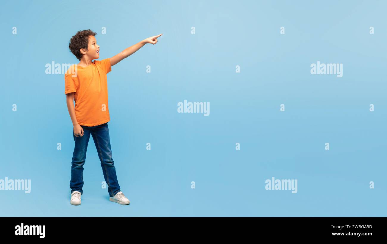 Excited boy pointing in the air at free space on blue backdrop Stock ...