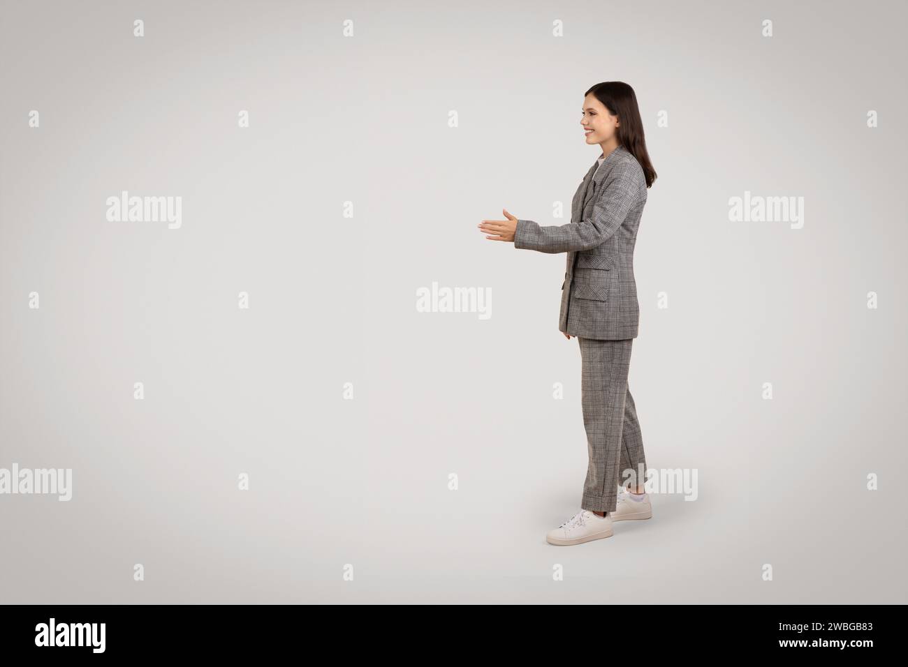 Side view of woman in suit extending hand, grey background Stock Photo ...