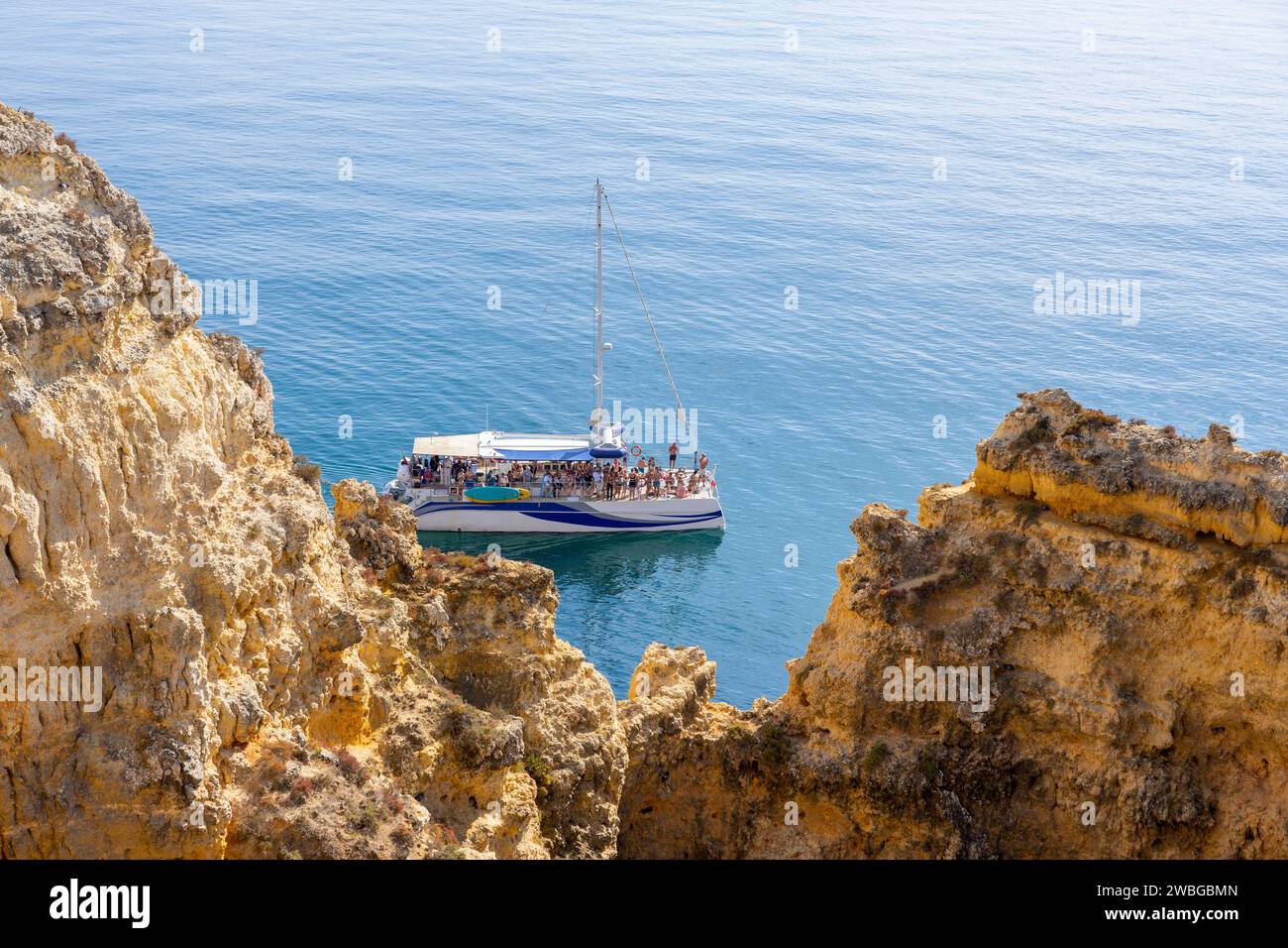 Boat with tourists on the beautiful coast of the Algarve region. Huge ...