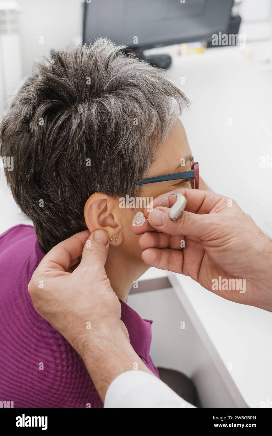 Otolaryngologist puting Modern miniature hearing aids for mid aged ...