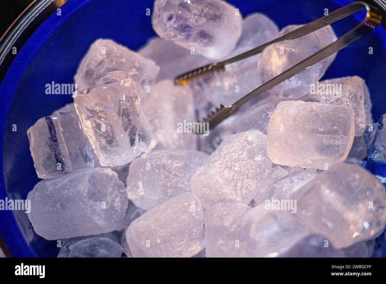 blue bucket with various ice cubes and tongs Stock Photo - Alamy
