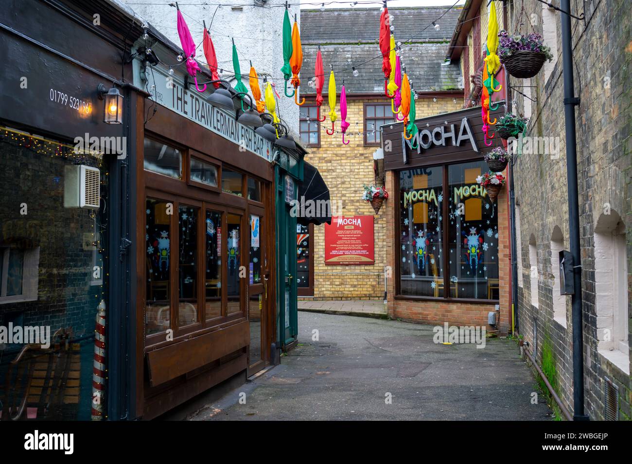 Colorful closed umbrellas hanging over an alleyway off the high street ...