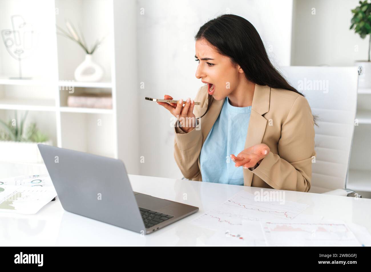 Speakerphone concept. Irritated angry young woman of indian or arabian ...