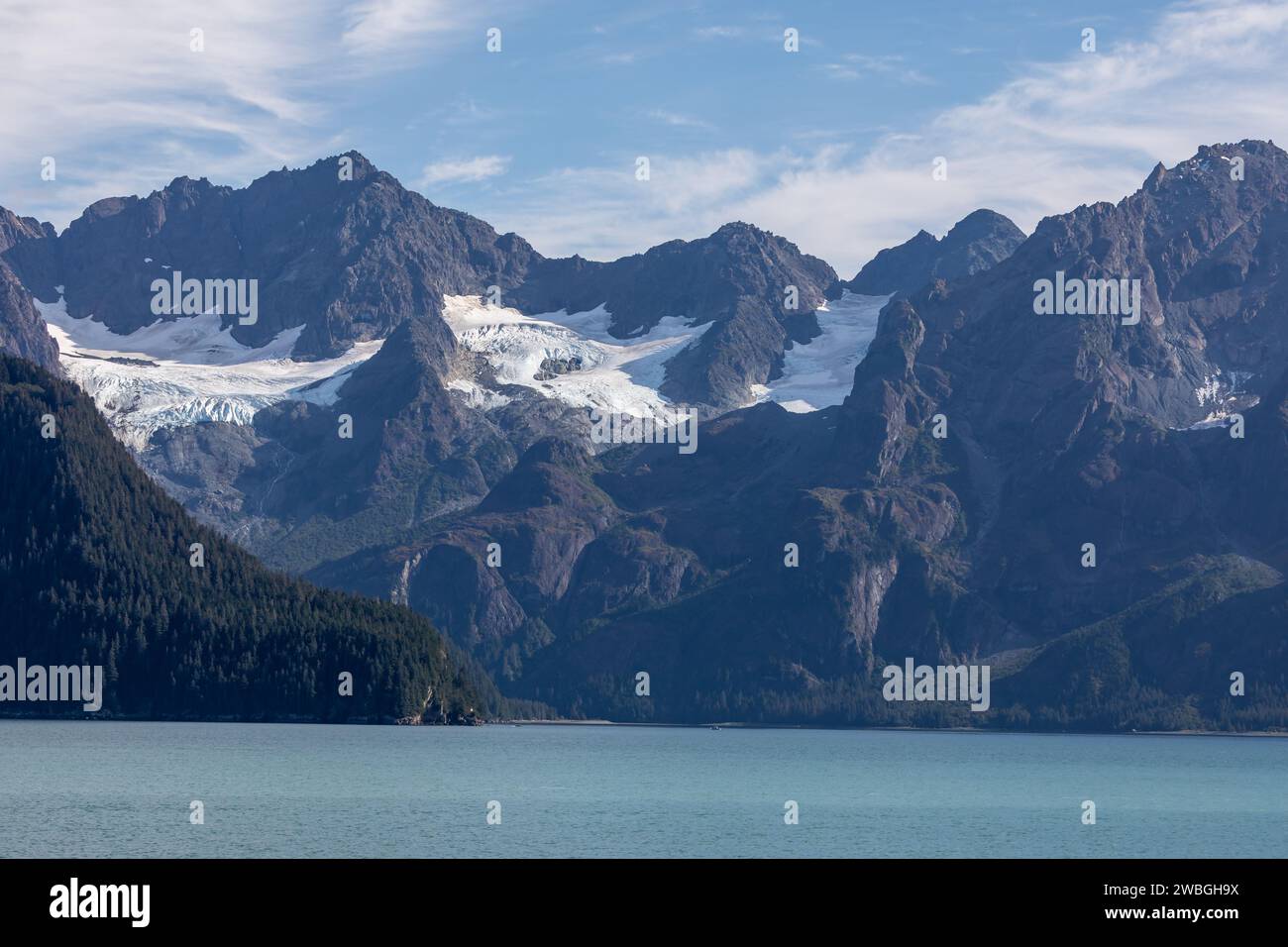Glaciers and jagged mountain peaks rise above calm blue waters of the ...