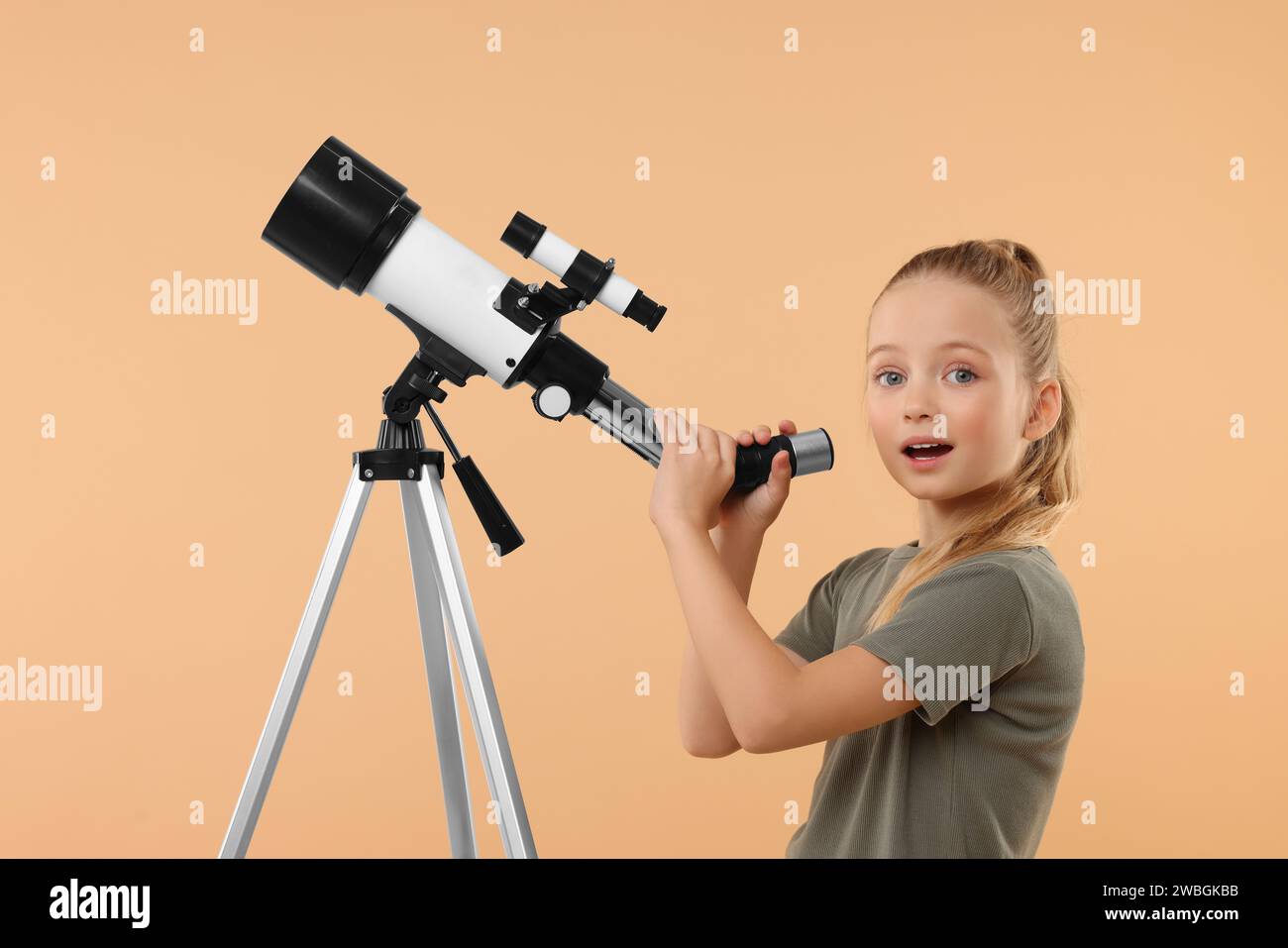 Surprised little girl with telescope on beige background Stock Photo ...