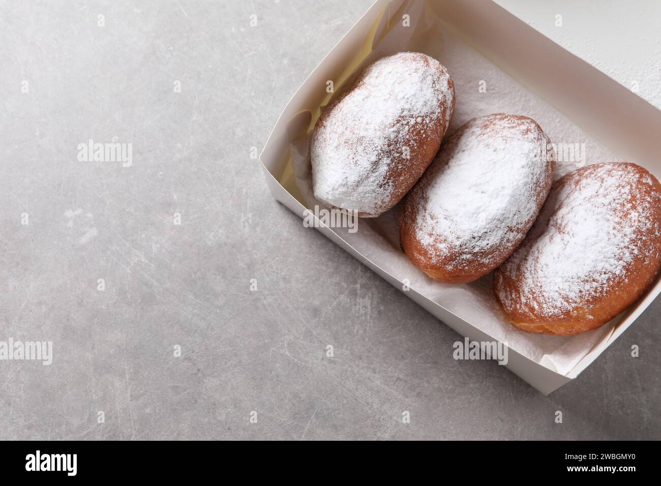 Delicious sweet buns in box on gray table, top view. Space for text ...