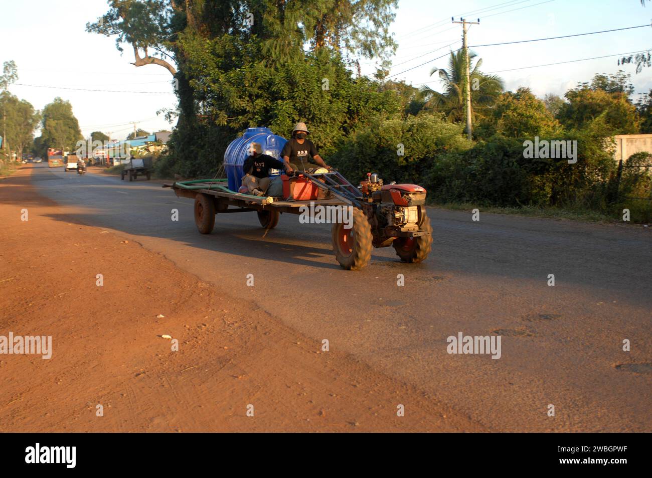 Man riding a tractor down the high street carrying a water tank, Beng ...
