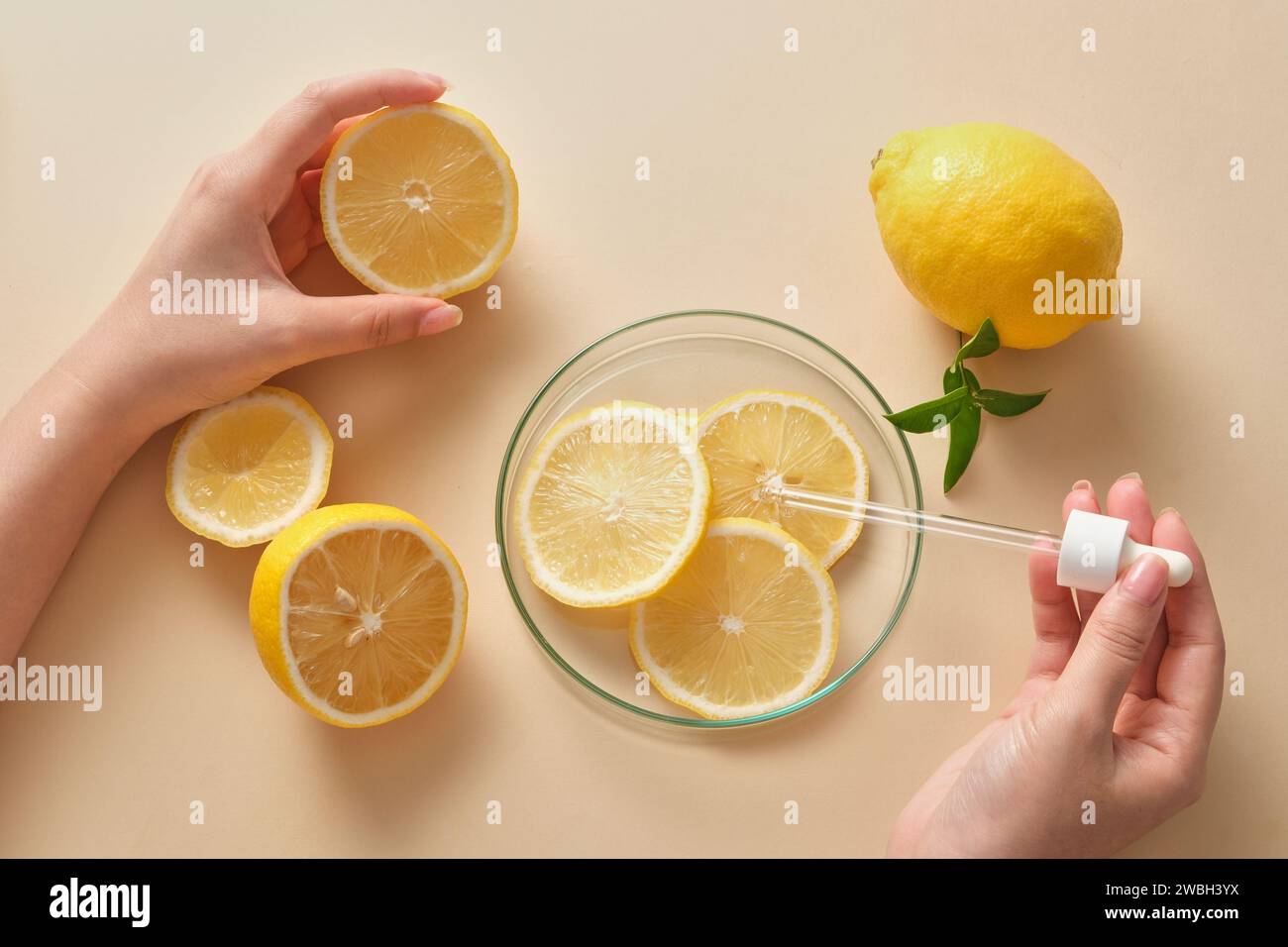 Female hand holding half a fresh lemon and a dropper with slices of ...